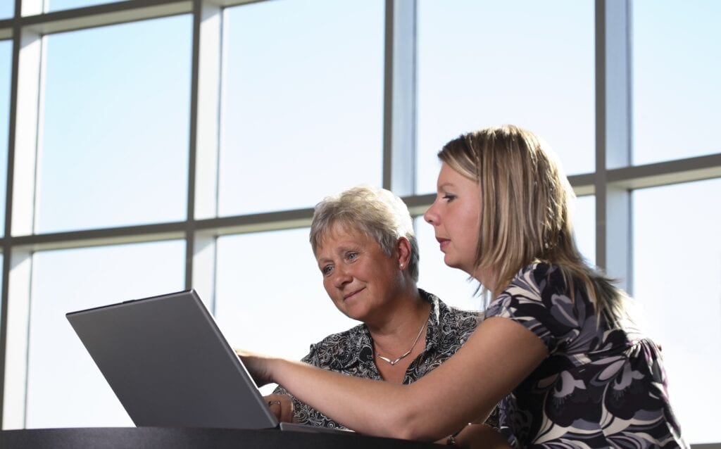 two women at a computer - Boomers' Social Media Tutor